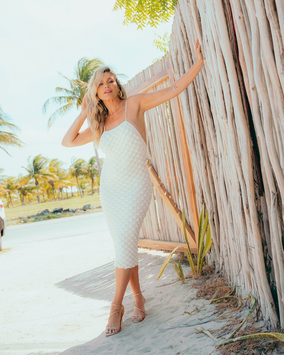 Flávia Alessandra posa de vestido branco com pé na areia no México ...